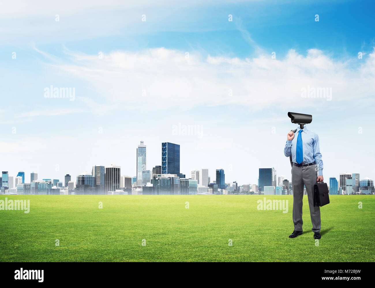 Camera headed man standing on green grass against modern cityscape ...