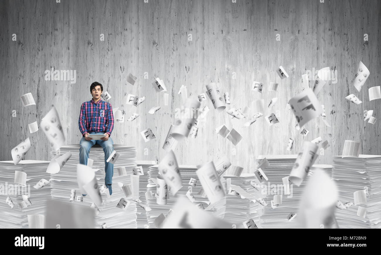 Attractive man sitting on pile of paper documents Stock Photo - Alamy