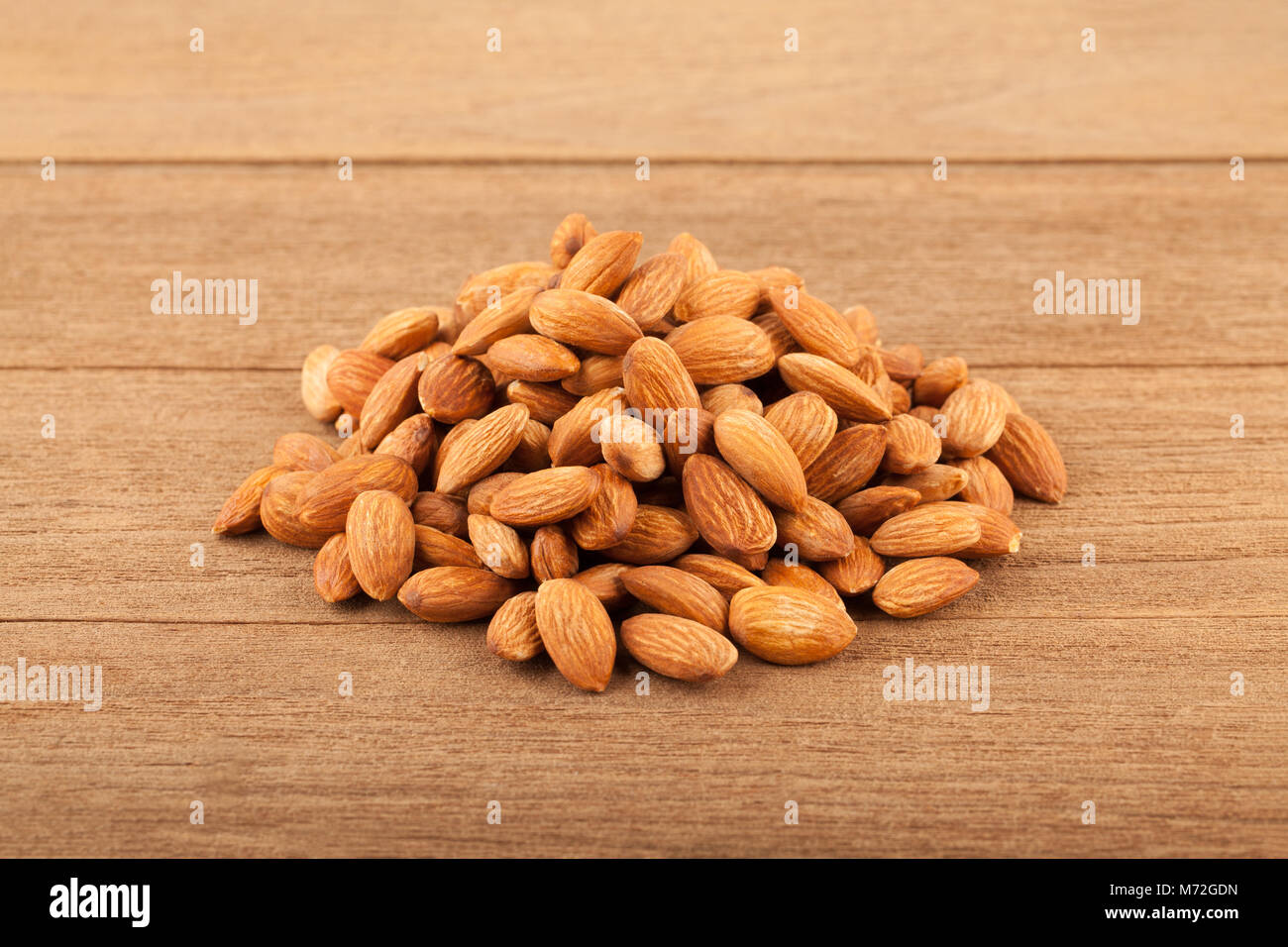 Heap of almonds seed on wood background Stock Photo - Alamy