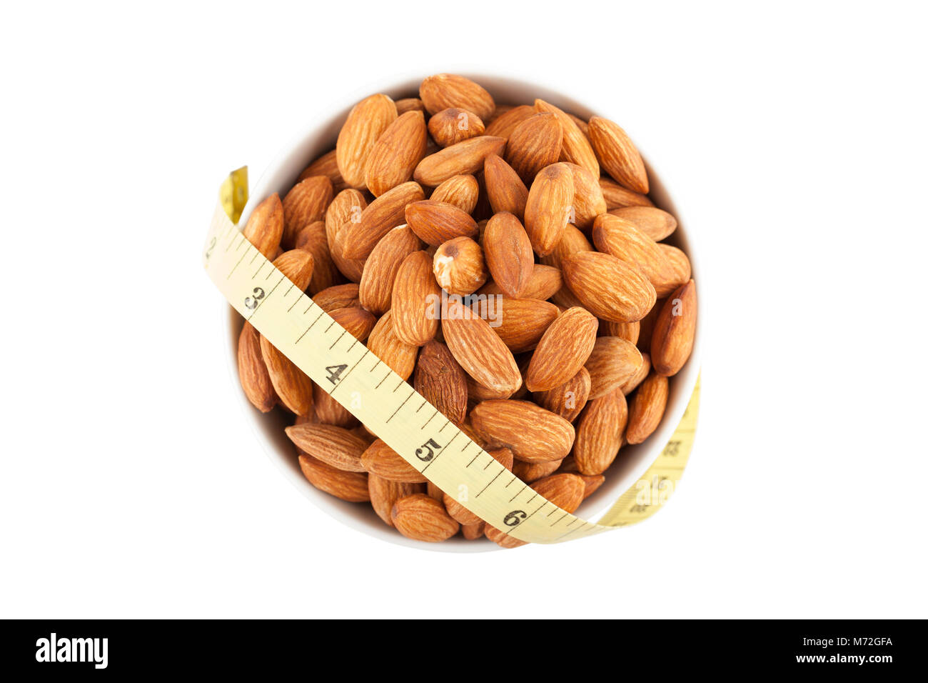 Top view of almonds seed in white ceramic bowl with measurement tape ...