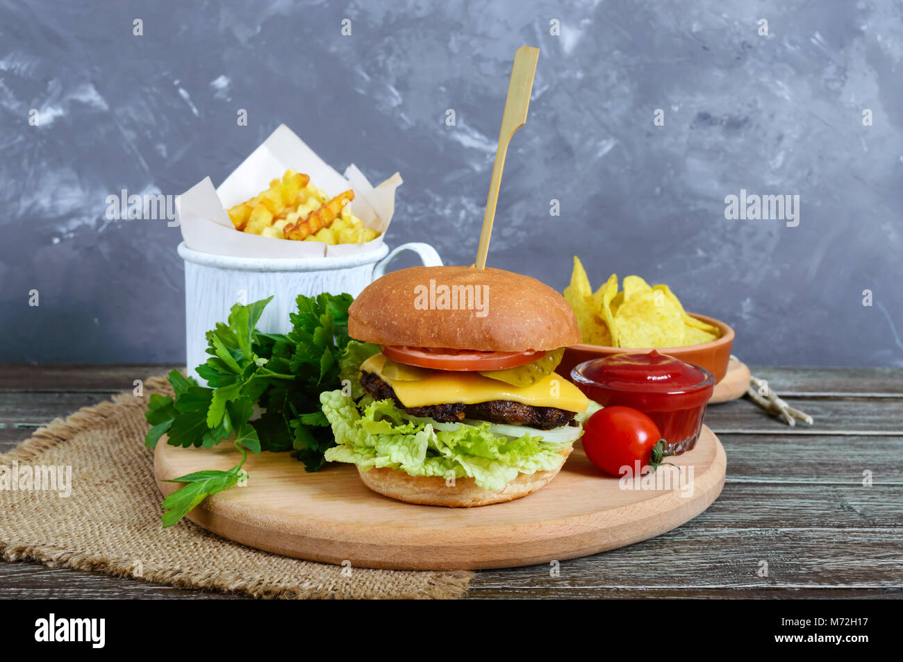 Burger, french fries, chips, sauce on a wooden background. Street food ...