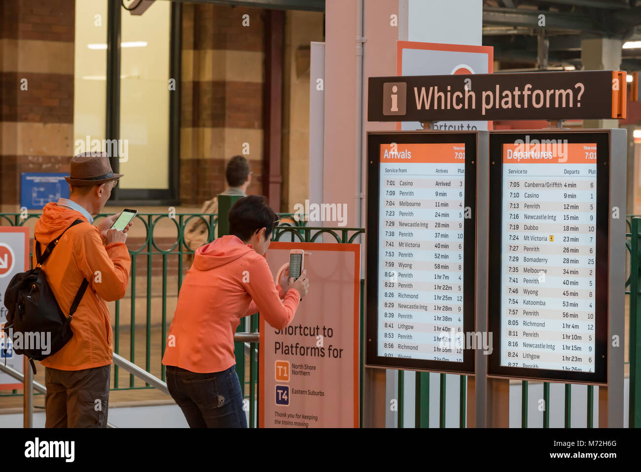 People using smart phones at a train timetable indicator board at ...