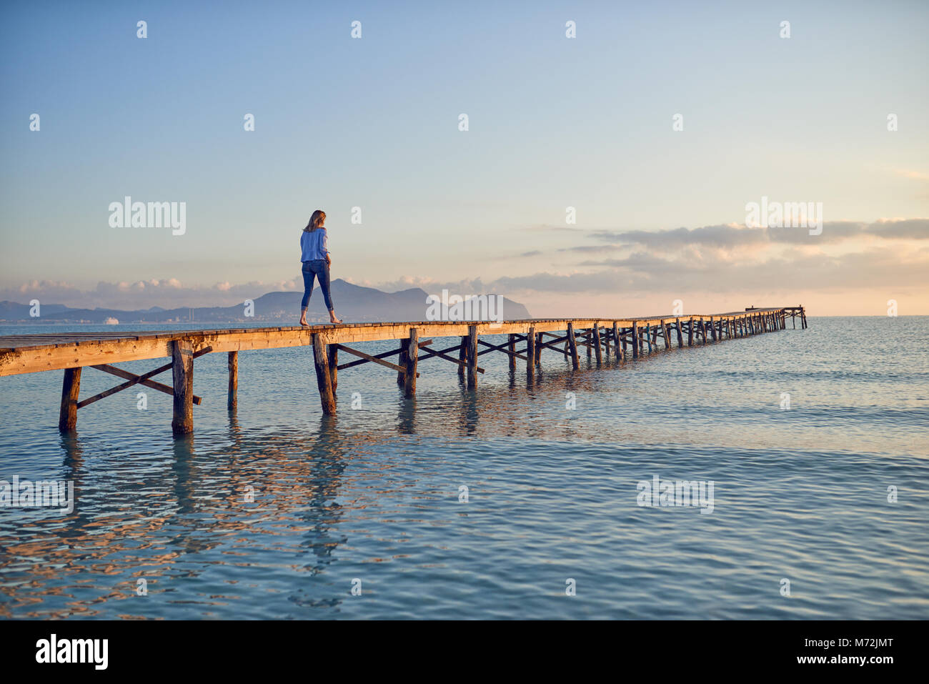 Woman walking away from the camera along a wooden pier or boardwalk at ...