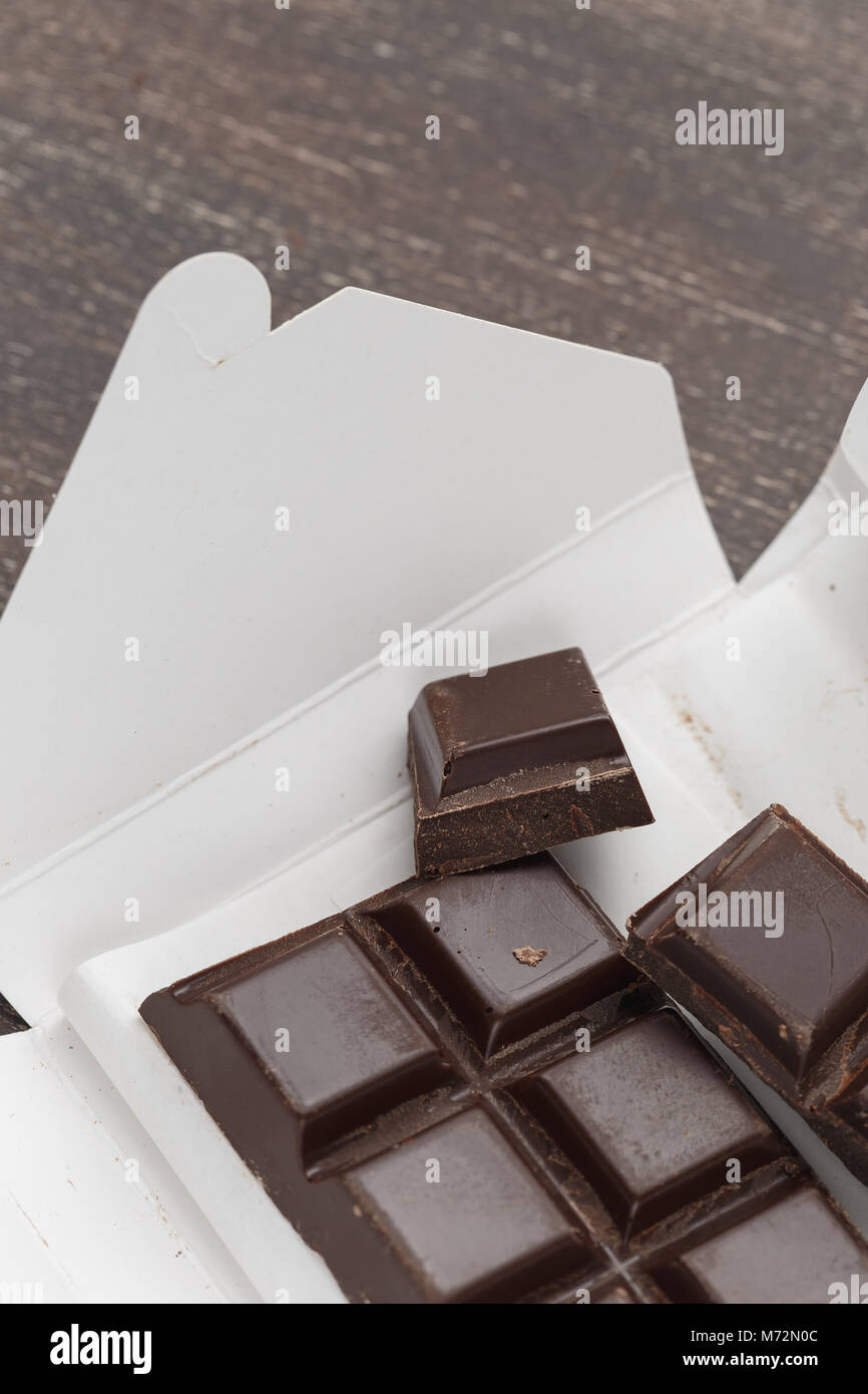 Open carton box with dark chocolate bar inside on grey wooden ...