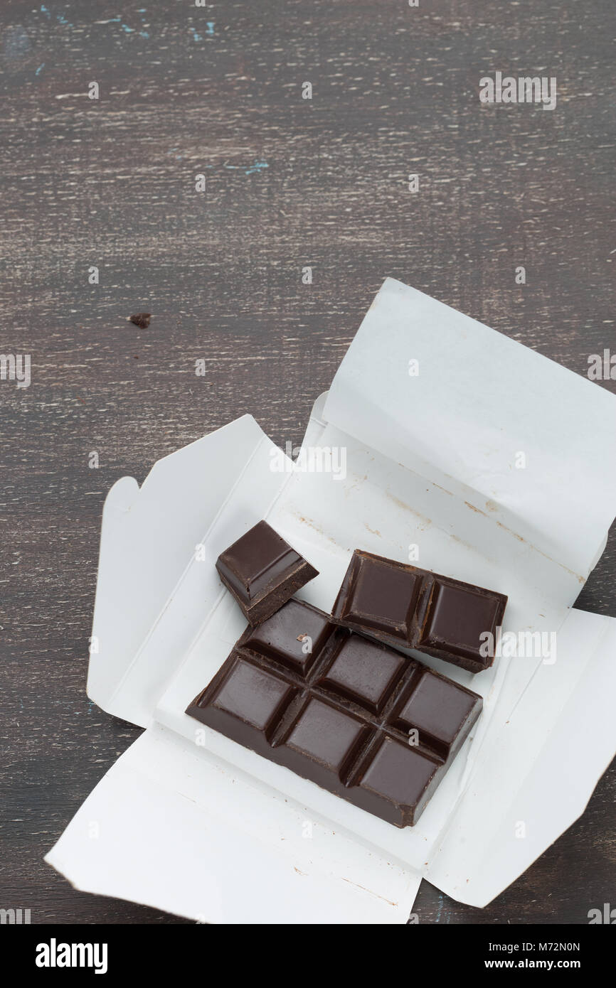 Open carton box with dark chocolate bar inside on grey wooden ...