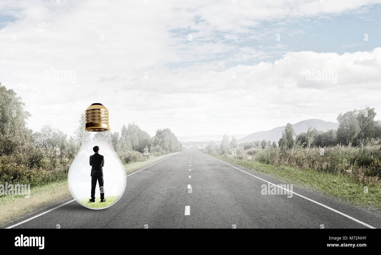 Young businessman trapped inside of light bulb on asphalt road Stock ...