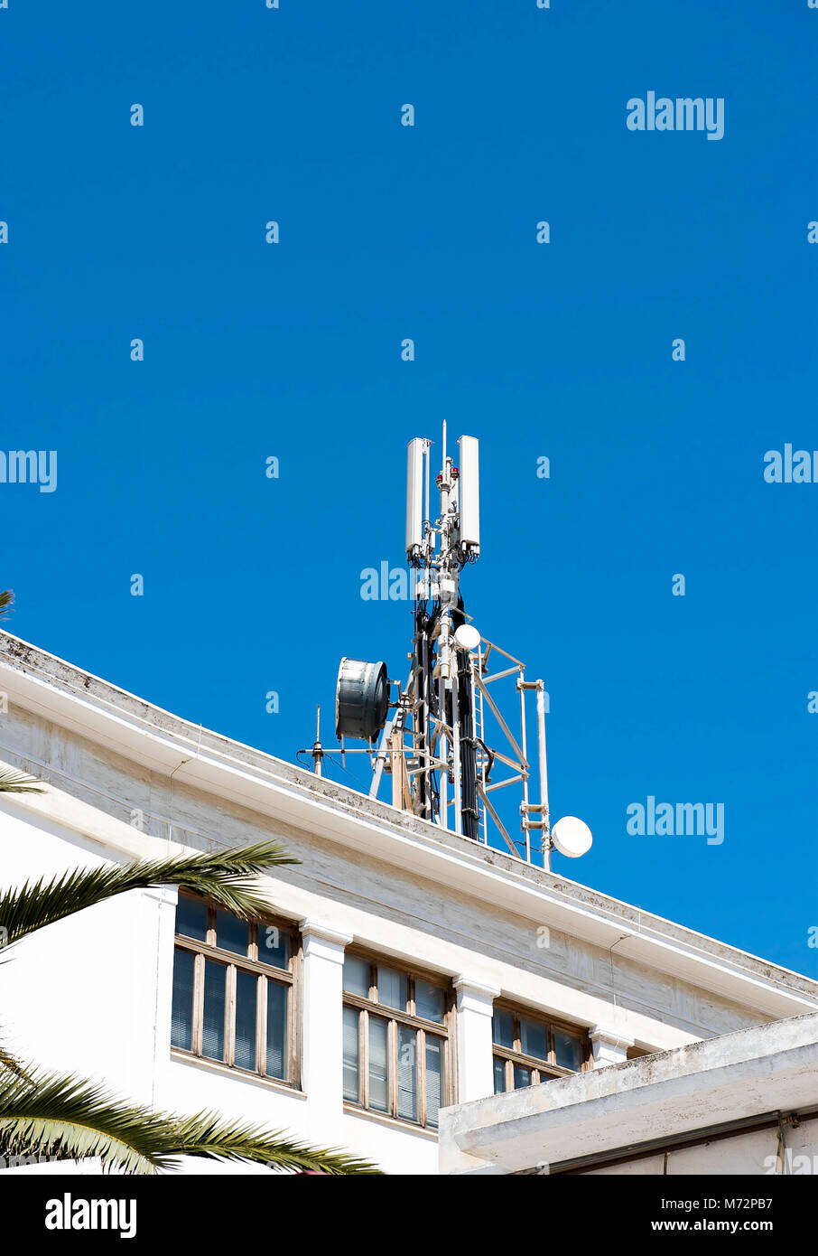 Cell phone telecommunications antennas and repeaters on building against clear blue sky Stock ...
