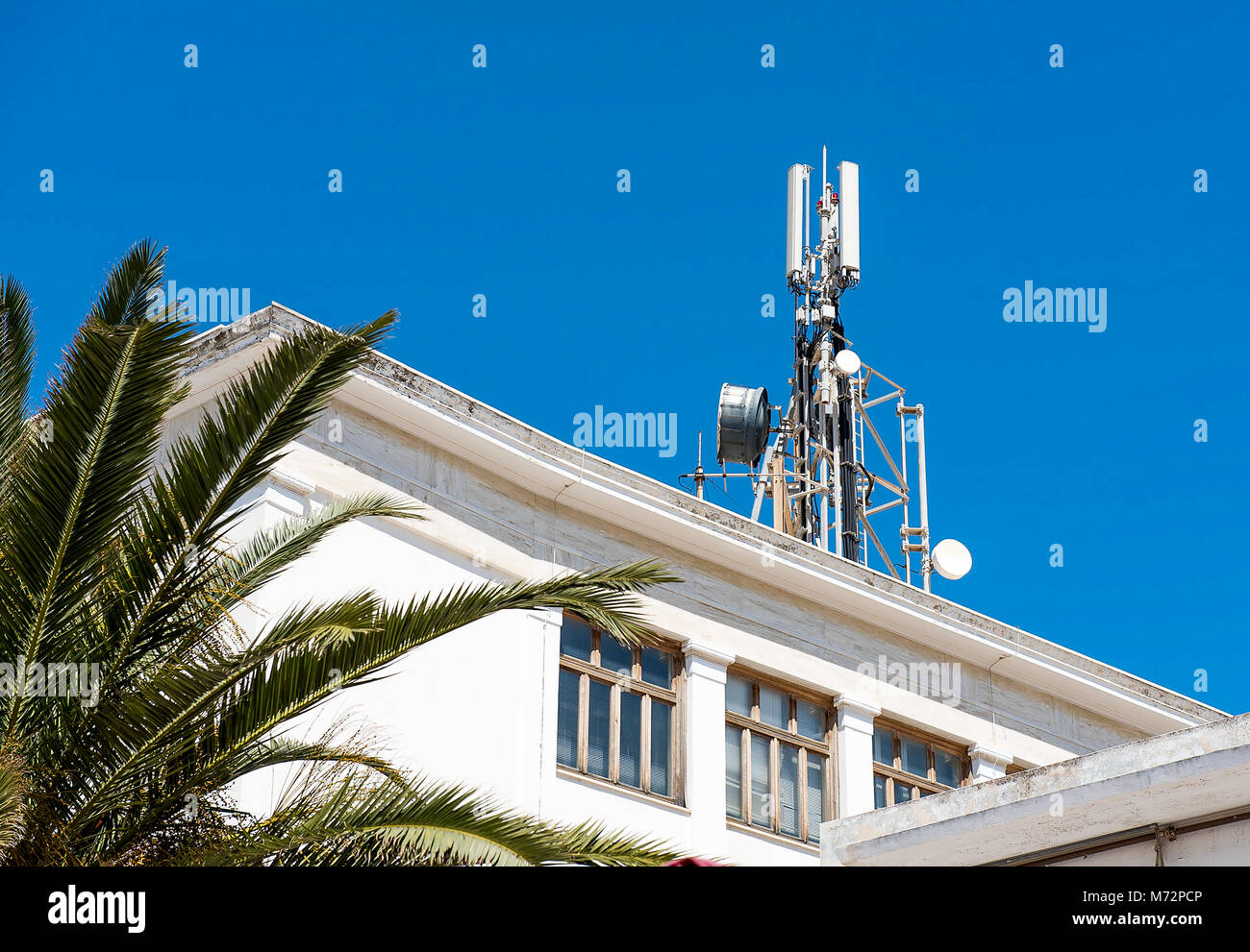 Cell phone telecommunications antennas and repeaters on building against clear blue sky Stock ...