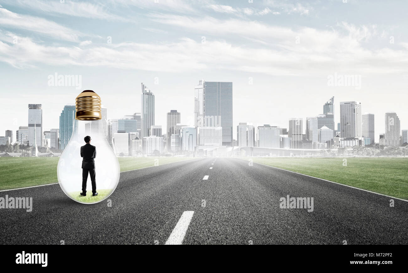 Young businessman trapped inside of light bulb on asphalt road Stock ...