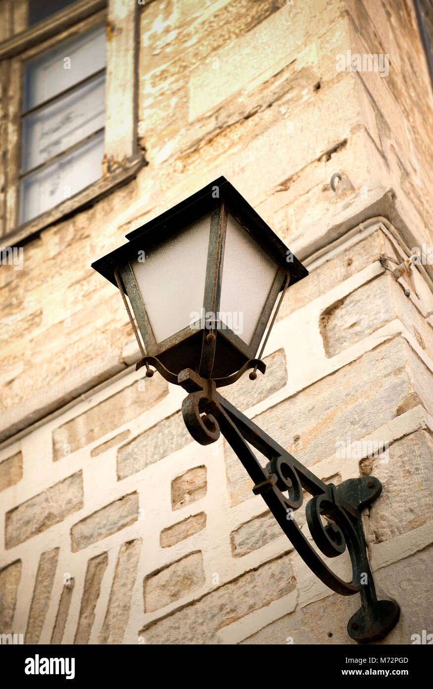 Street lamp of vintage design lighted on the stone wall in the ...