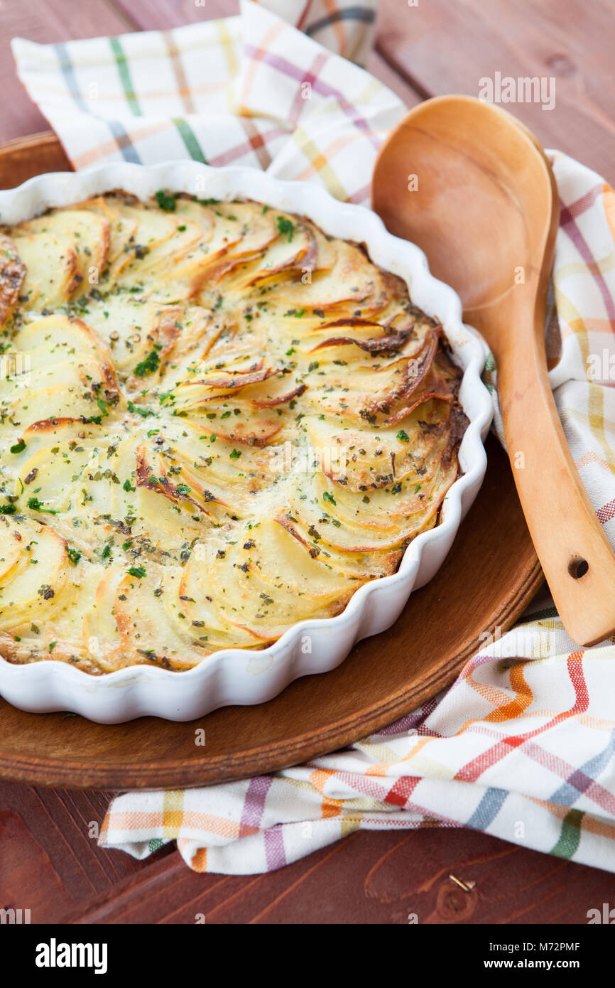 Potato gratin in round baking dish on rustic woodden background Stock ...