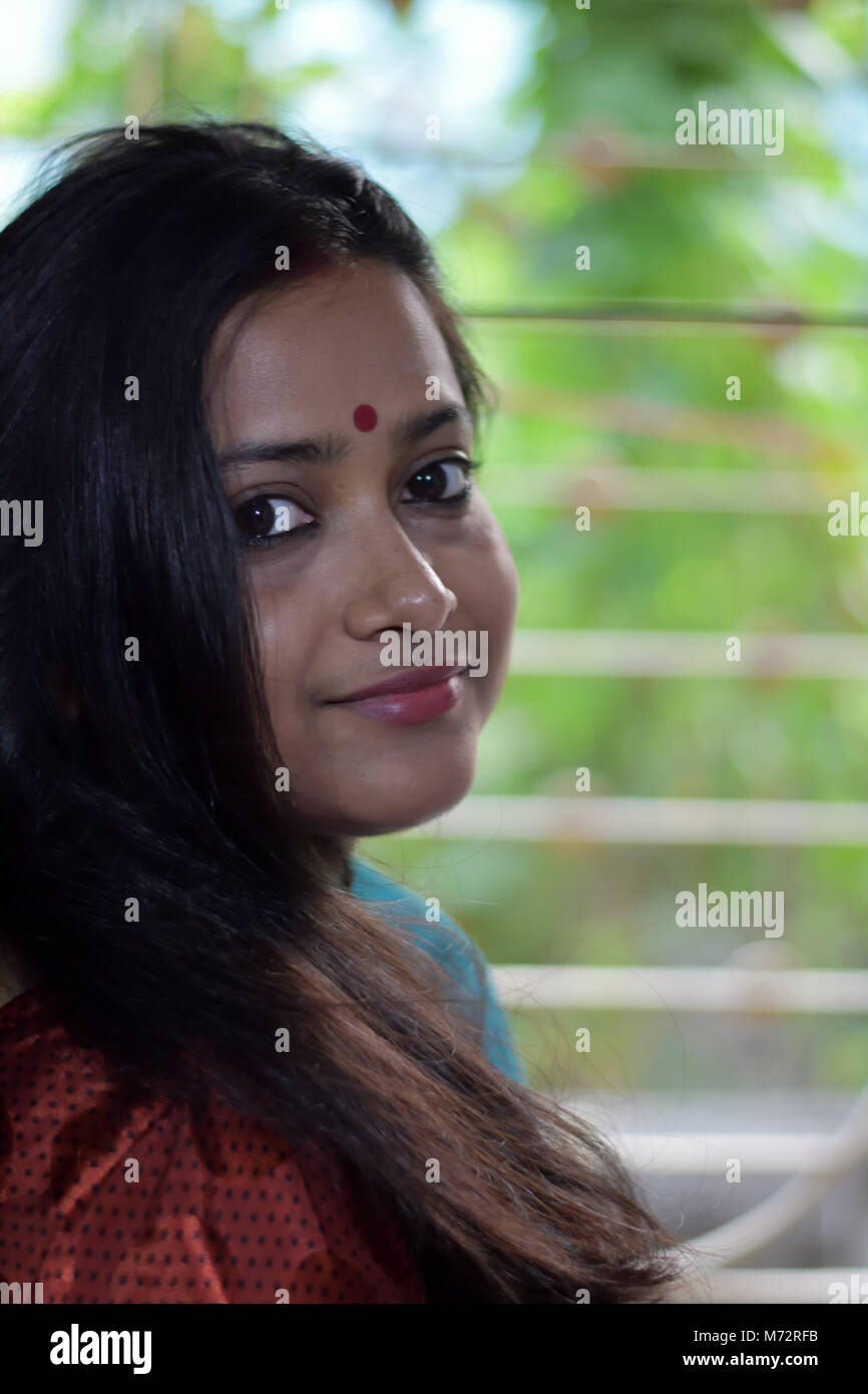 A beautiful bengali lady, standing infront of a window is turning her ...