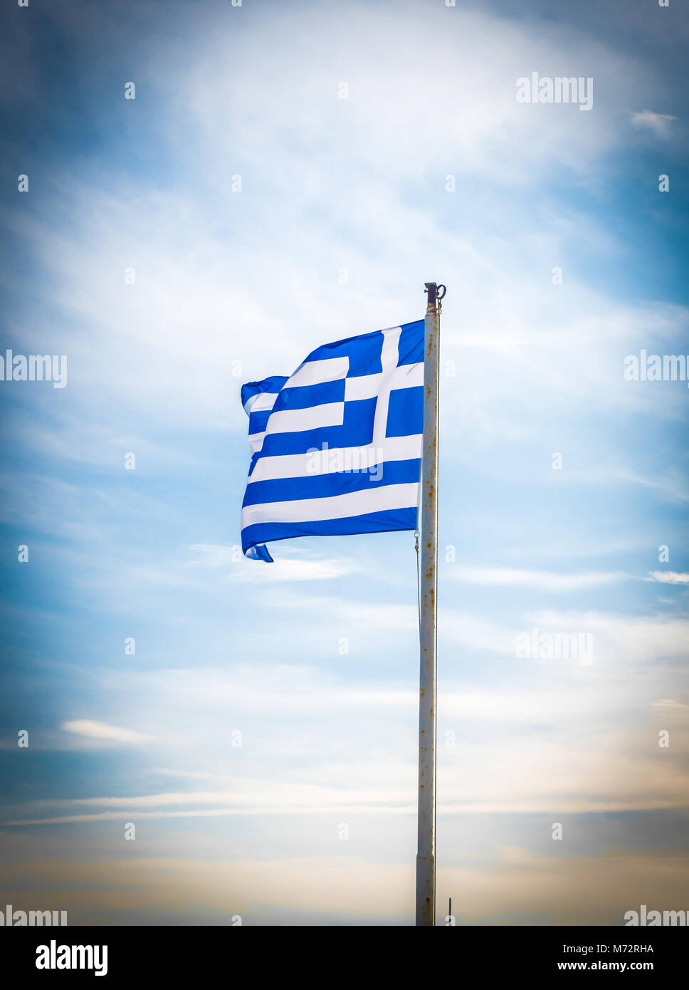 Greek flag waving in the wind in a blue sky and white clouds around ...