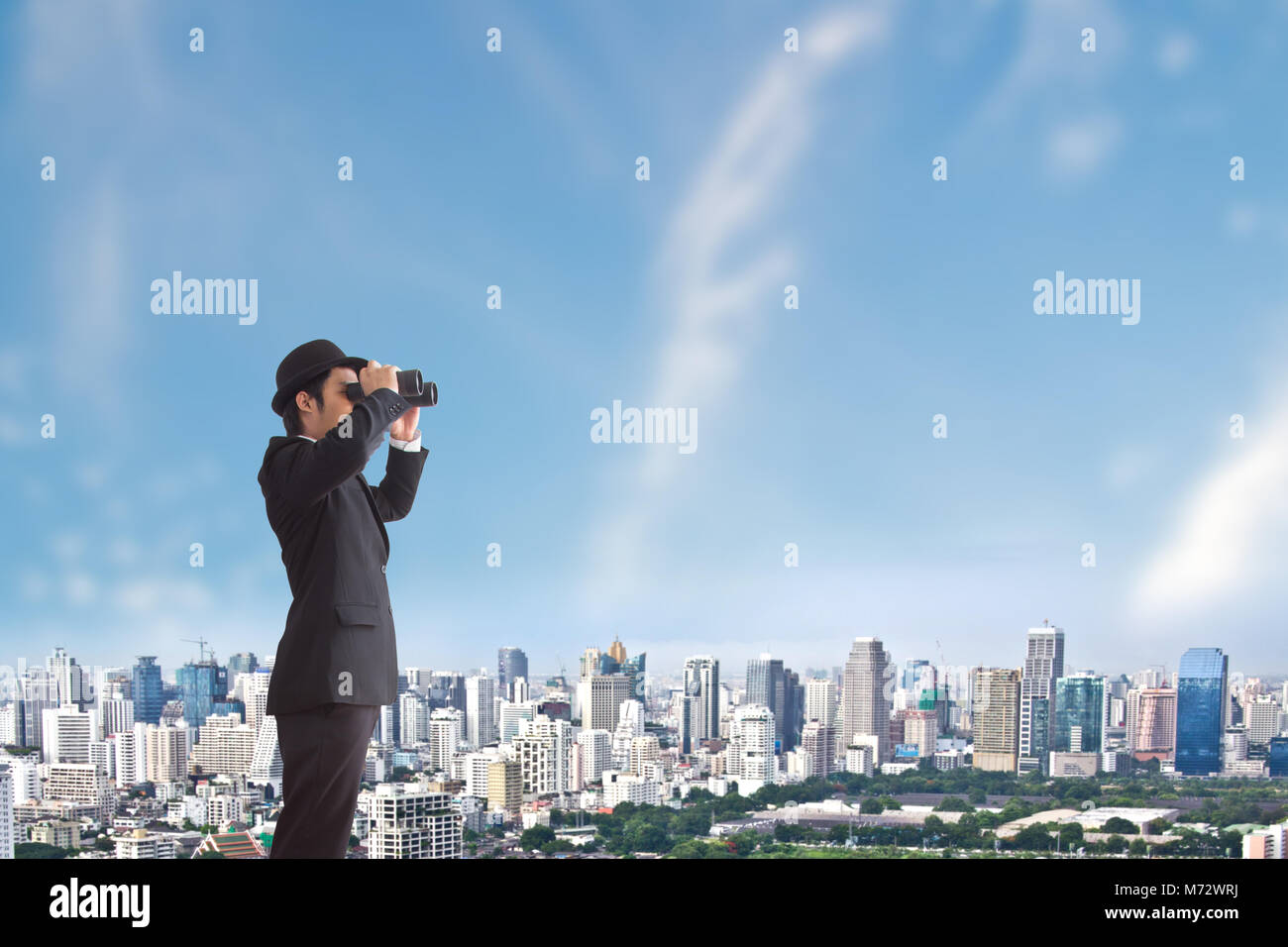 Businessman using binoculars looking for something Stock Photo - Alamy