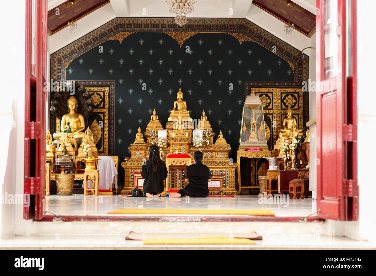 Two women in black clothes sitting in pray inside a temple of the Grand ...