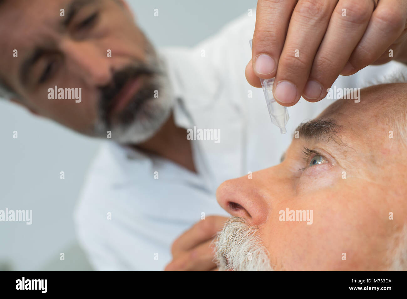 doctor giving elderly person eye drops Stock Photo - Alamy