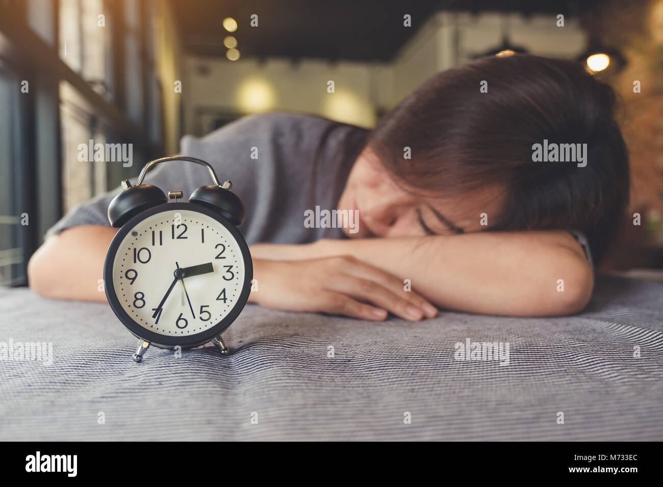 An Asian woman taking a nap on the table with black alarm clock Stock ...
