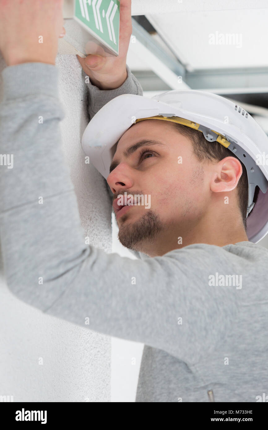 Man fitting directional exit sign Stock Photo - Alamy