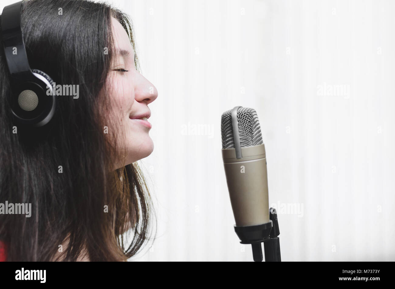 Woman singing at a studio microphone, wearing a headphone. Woman with ...