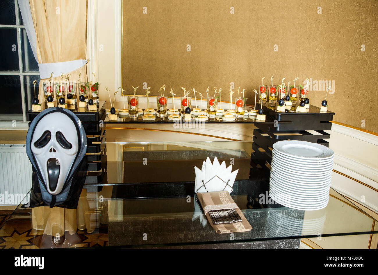 cheese snack, plates, cutlery, scary mask arranged on glass table on ...
