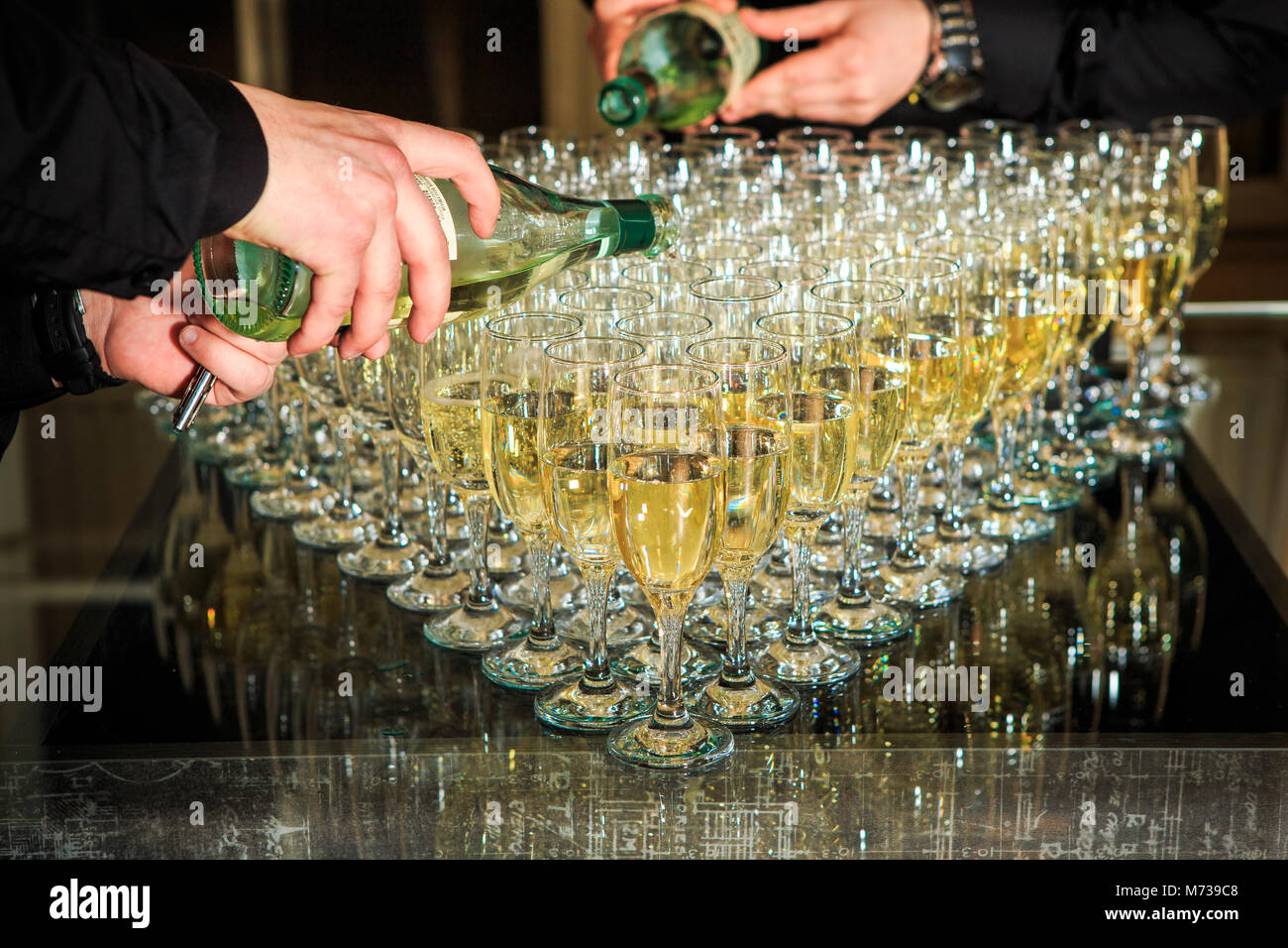 set of partially filled campaign glasses arranged in triangle on mirror ...