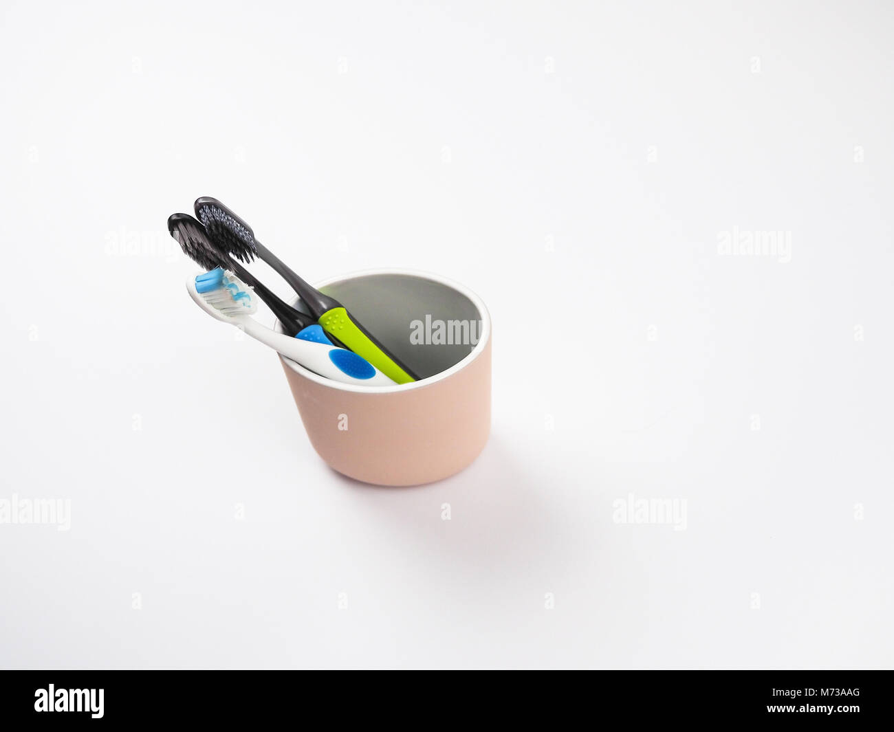 three toothbrush in cup on white background Stock Photo - Alamy