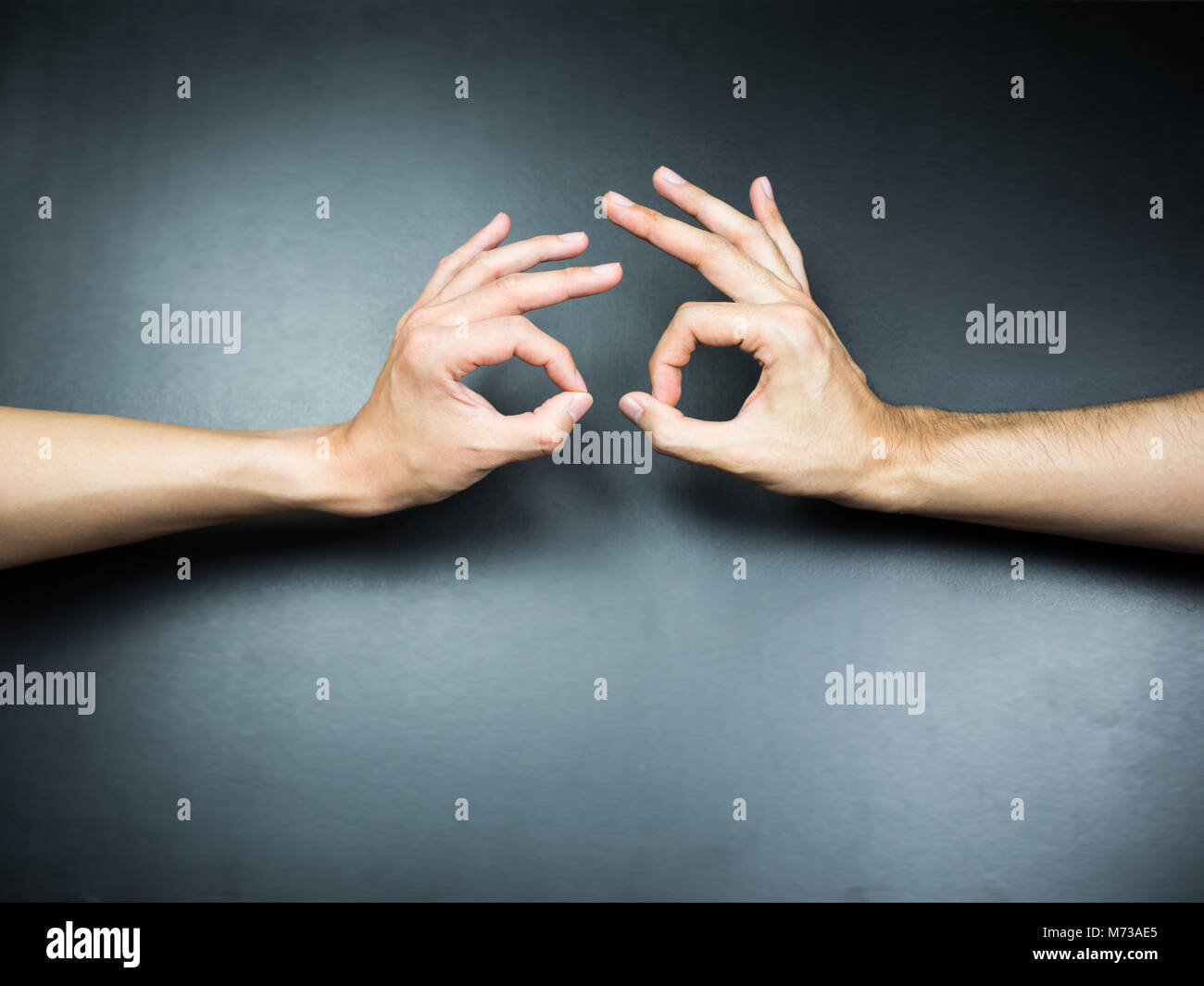 two OK hands gestures to each other on black background Stock Photo - Alamy