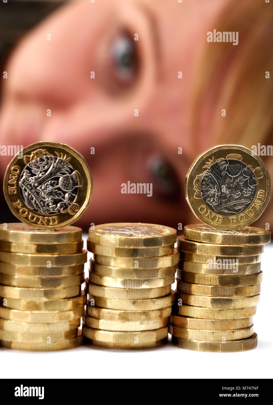 Stacks of one pound coins close up with woman's face in the background ...
