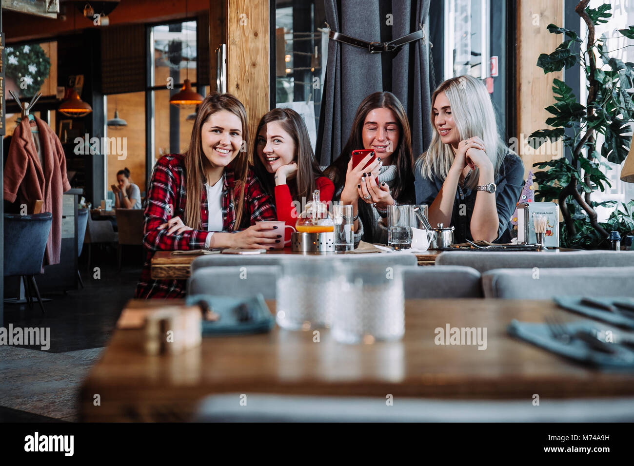 four friends in the cafe look at the camera and laugh Stock Photo - Alamy
