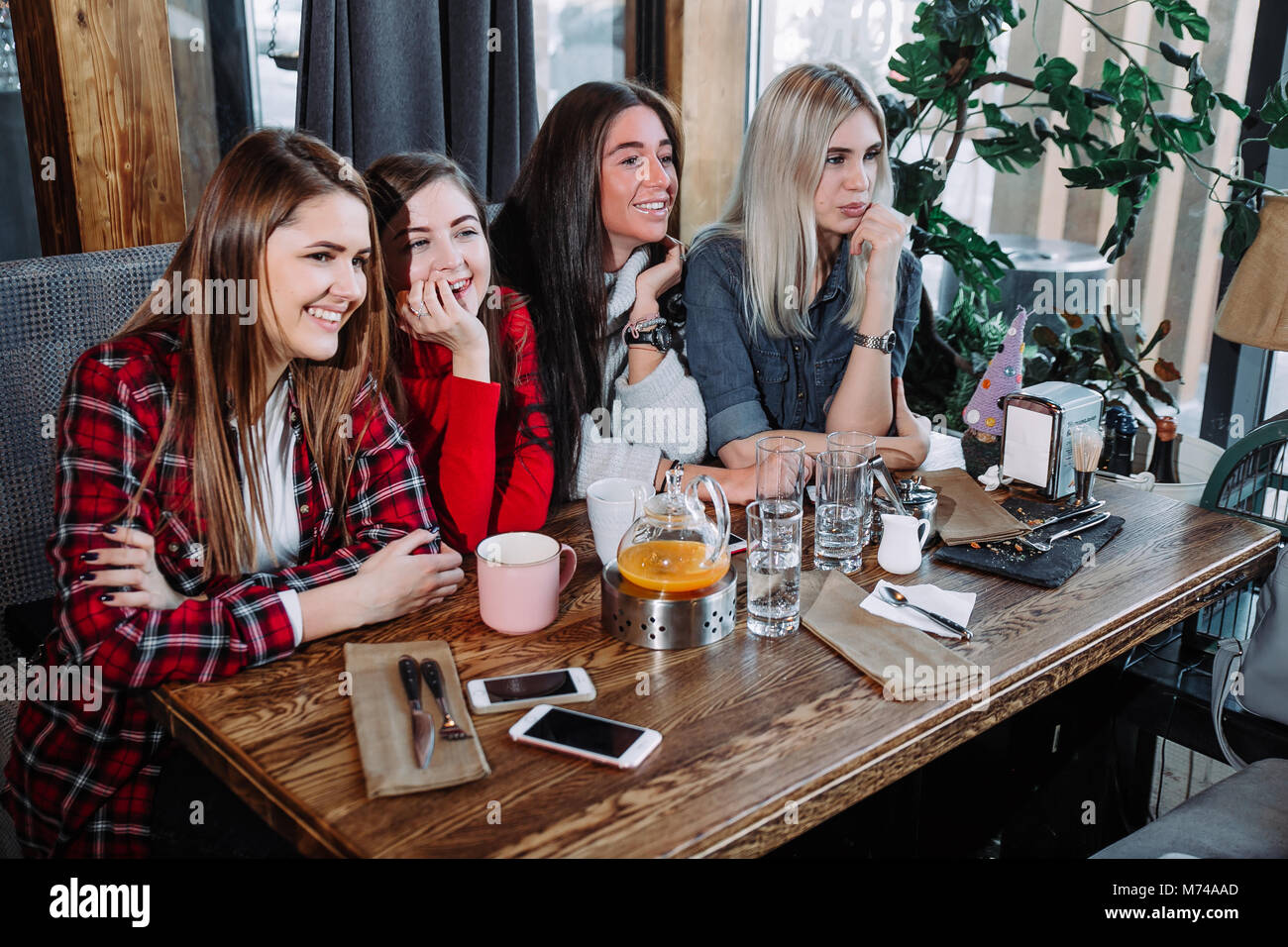 four friends in the cafe look at the camera and laugh Stock Photo - Alamy