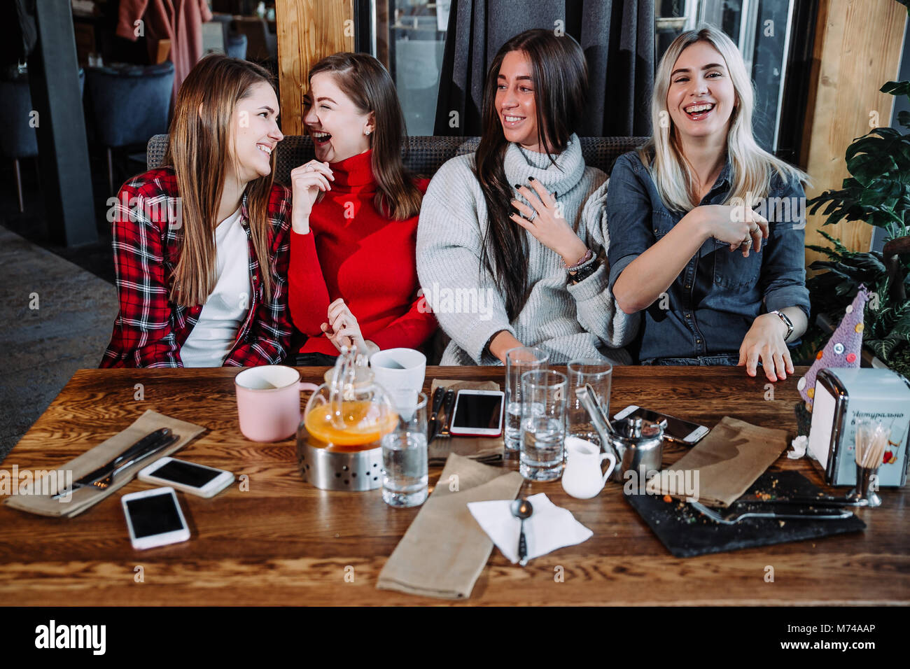 four friends in the cafe look at the camera and laugh Stock Photo - Alamy