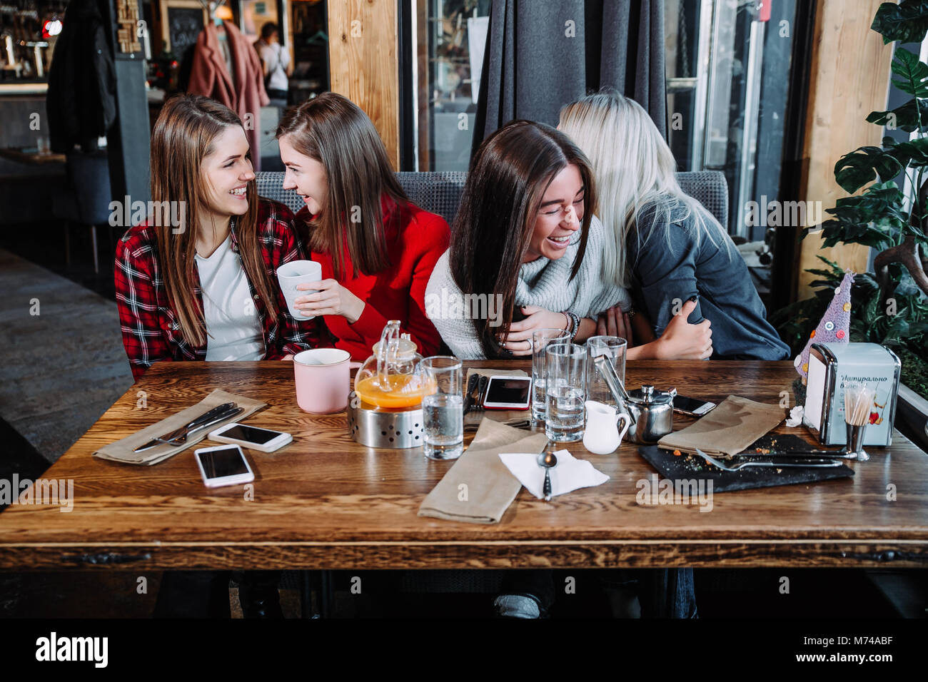 four friends in the cafe look at the camera and laugh Stock Photo - Alamy