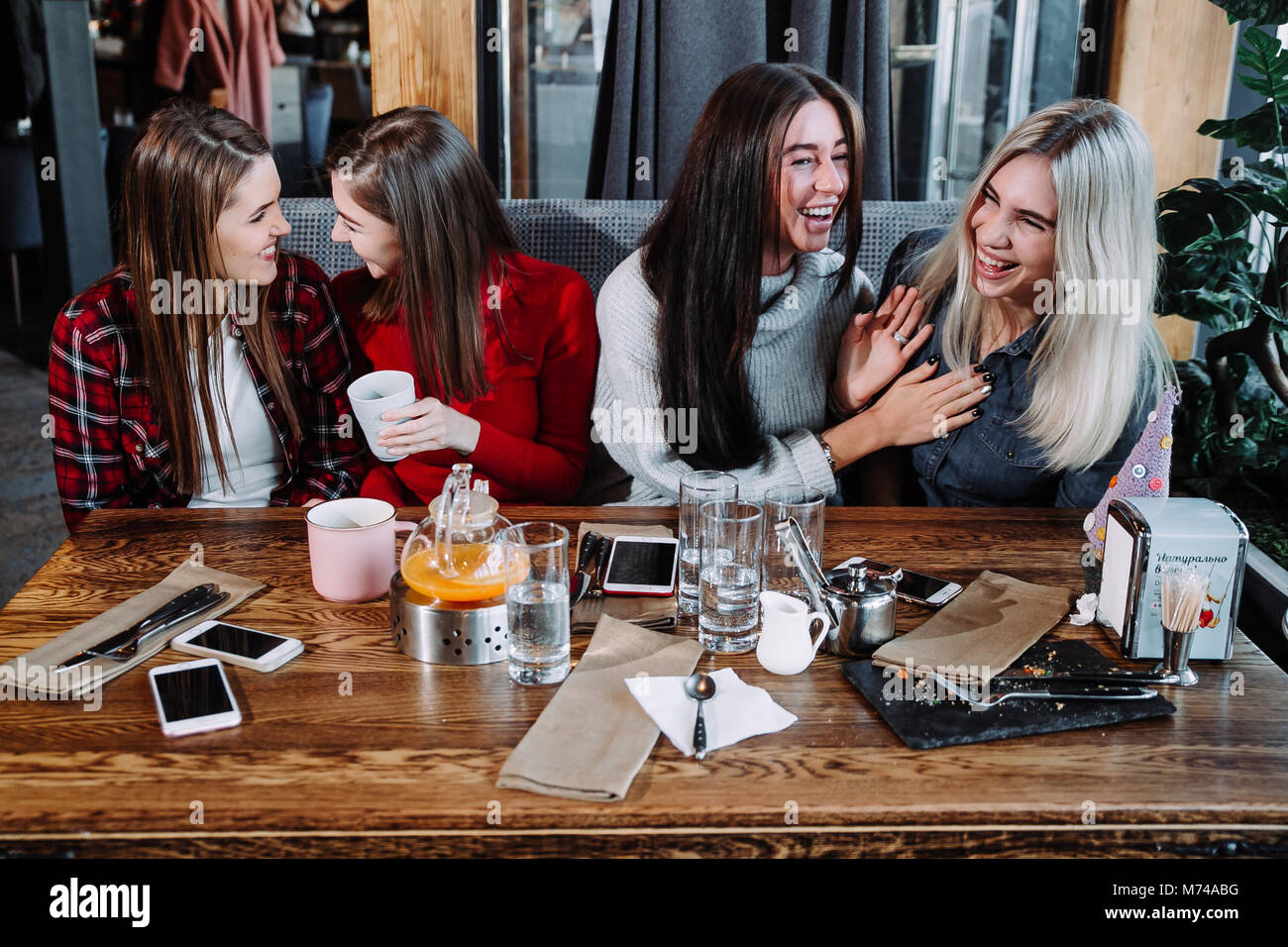 four friends in the cafe look at the camera and laugh Stock Photo - Alamy