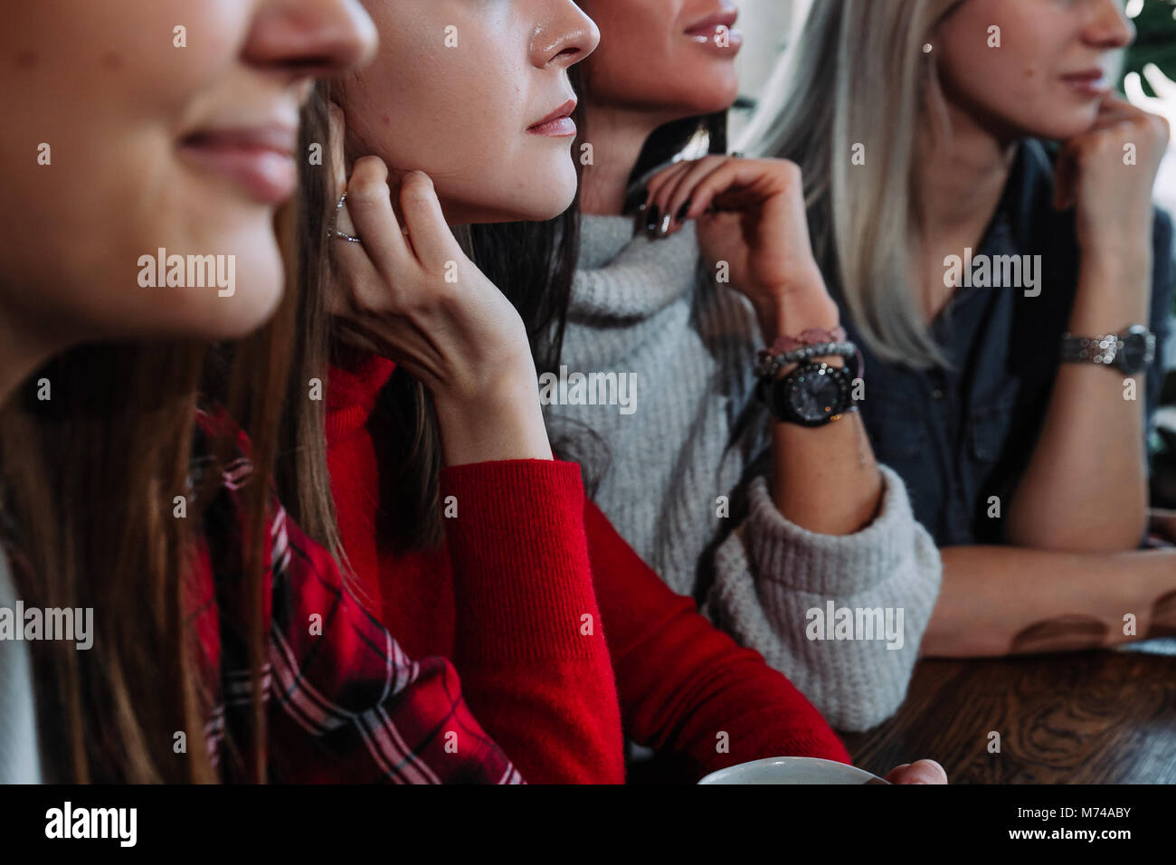 Side view of a Four smiling friends sitting by the table in cafe Stock ...