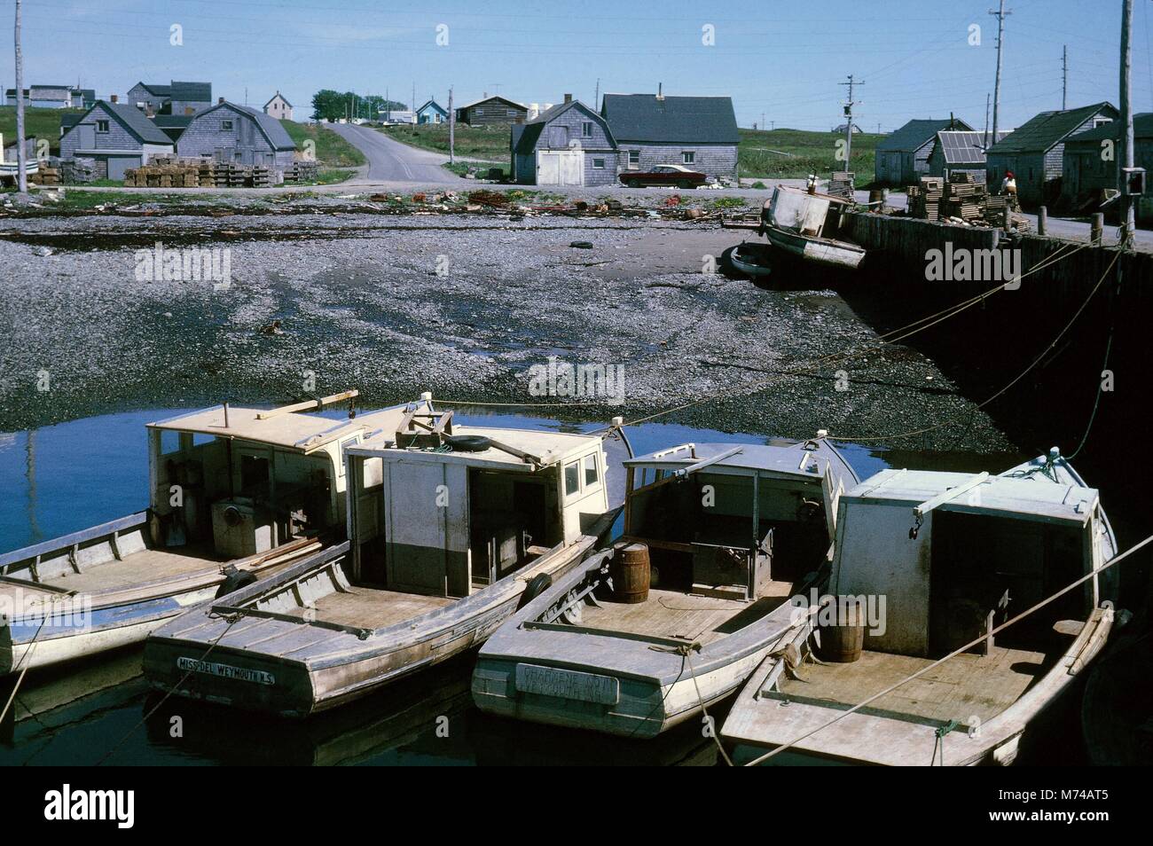 Four boats rest on the water well below the level of the dock they are ...