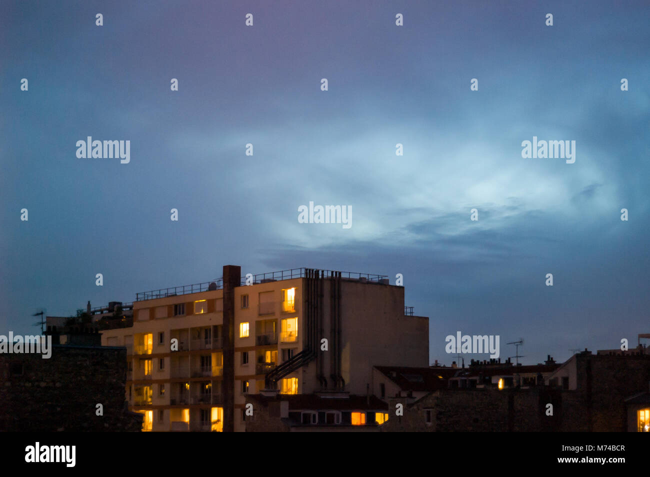 Night is falling on a residential building with illuminated rooms in a ...