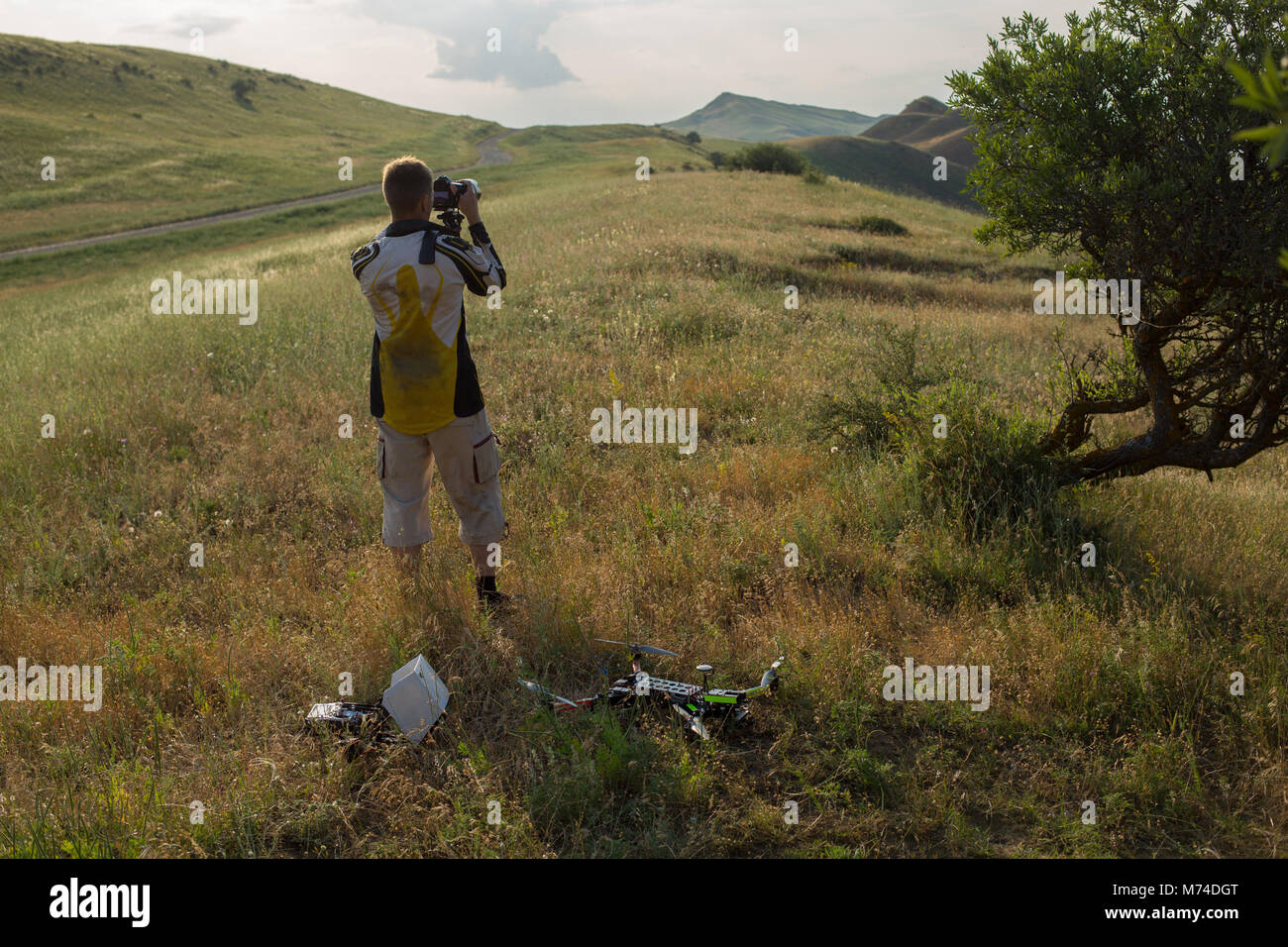 Cameraman in the sunny light rays yellow field in the mountains drone ...
