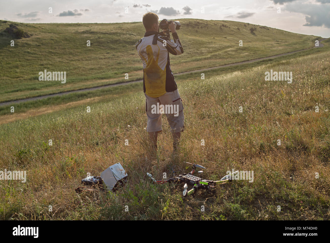Cameraman in the sunny light rays yellow field in the mountains drone ...