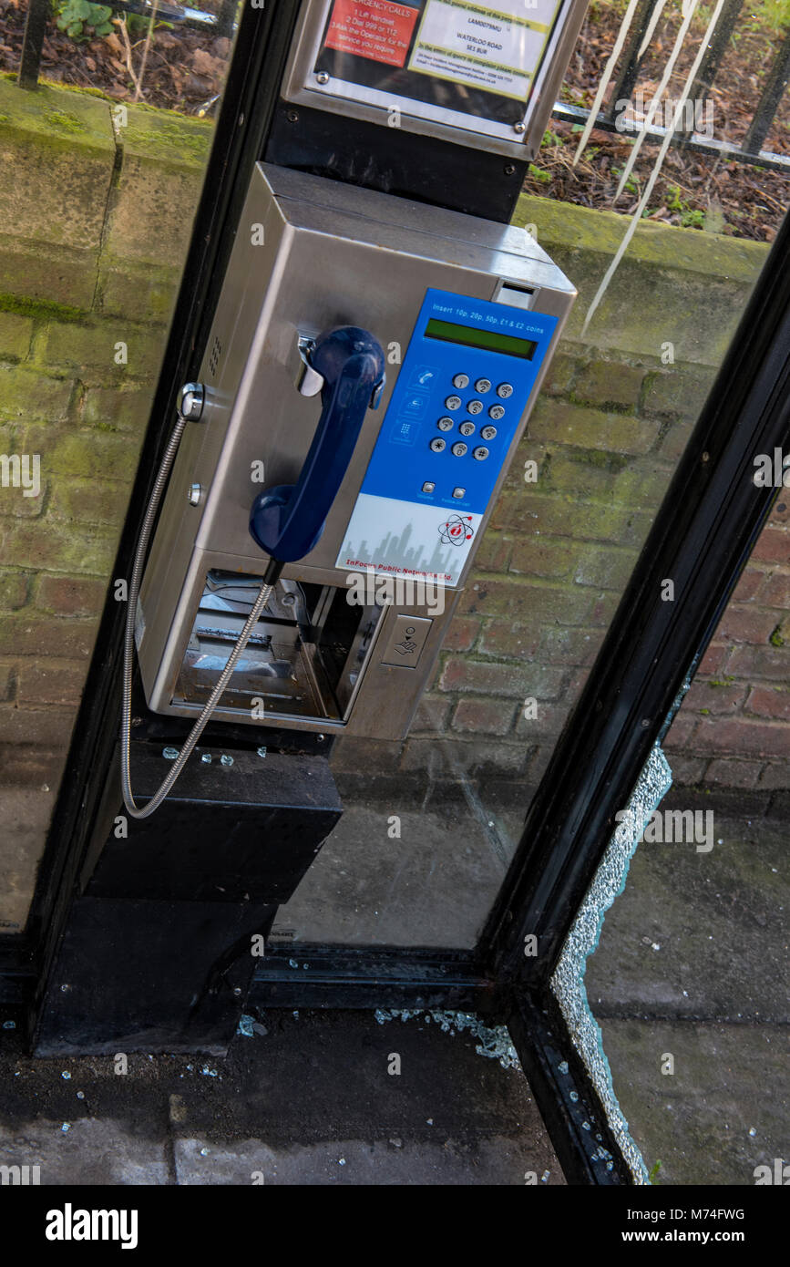 a vandalised phone or call box with broken glass and smashed window ...