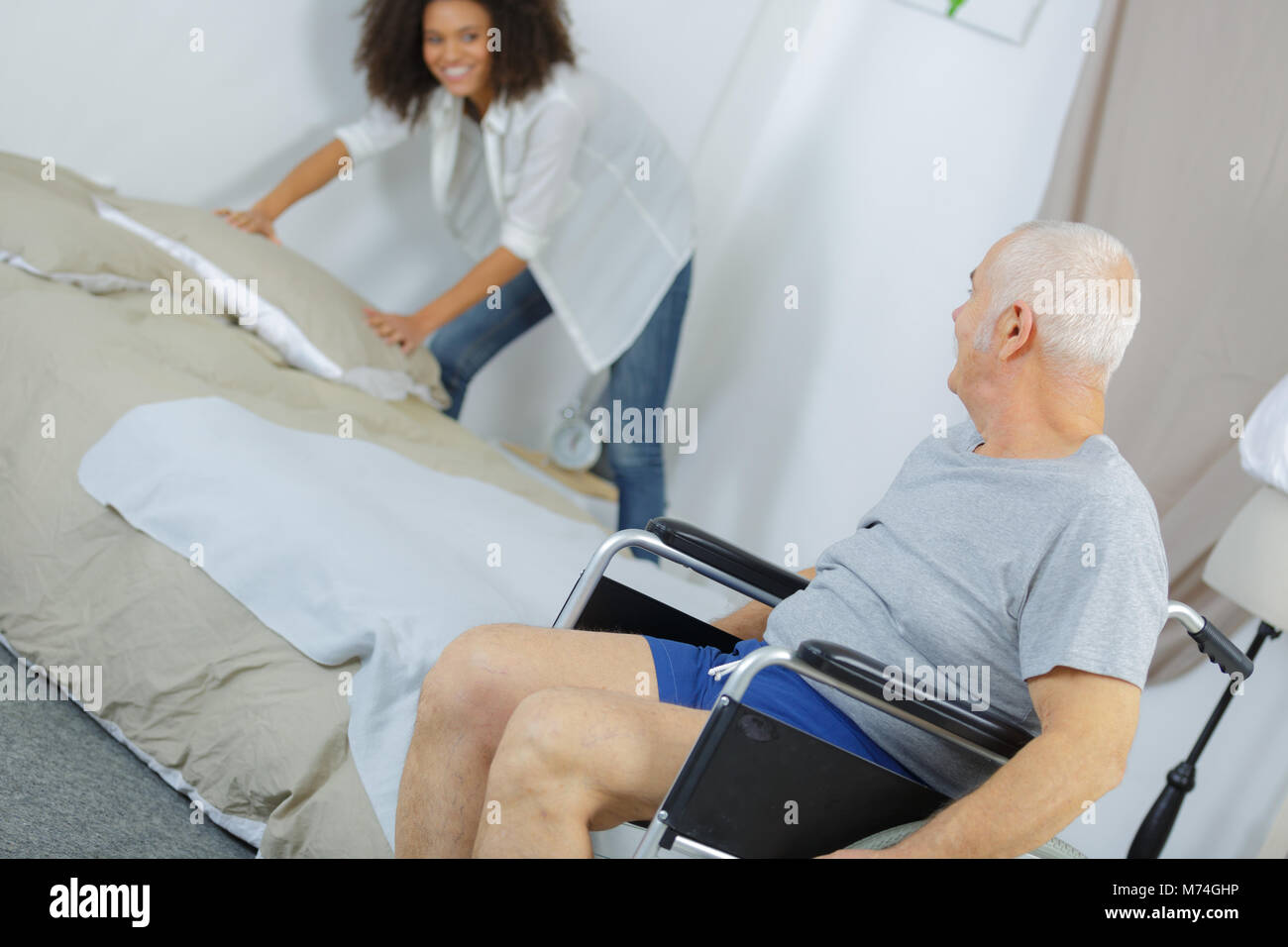 young female caregiver helping senior man at home Stock Photo - Alamy