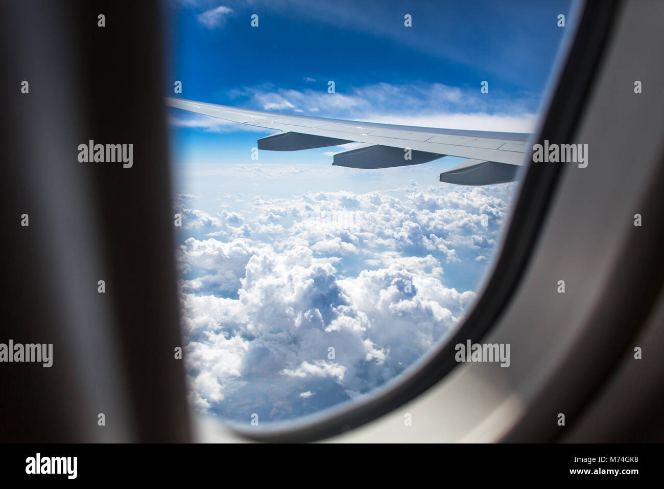 An airplane wing through airplane window with blue sky background Stock ...