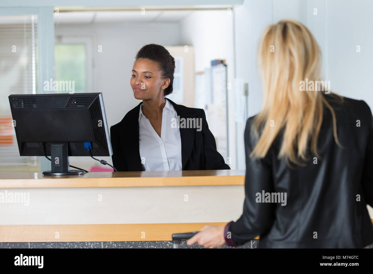female receptionist attending beautiful passenger Stock Photo - Alamy