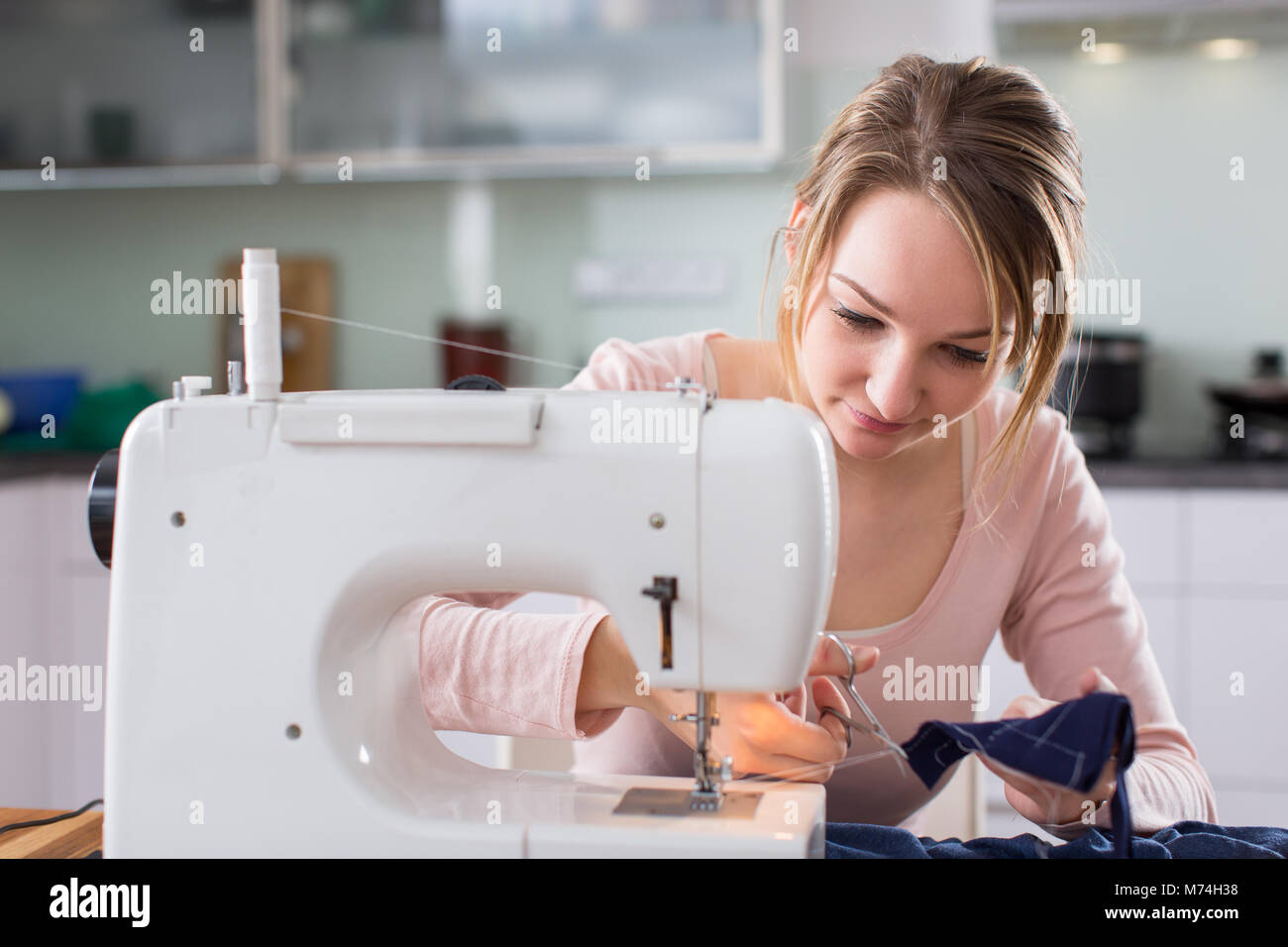 Beautiful young woman sewing clothes with sewing machine (color toned ...