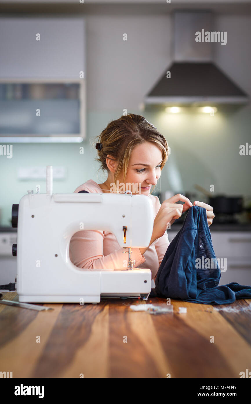 Beautiful young woman sewing clothes with sewing machine (color toned ...