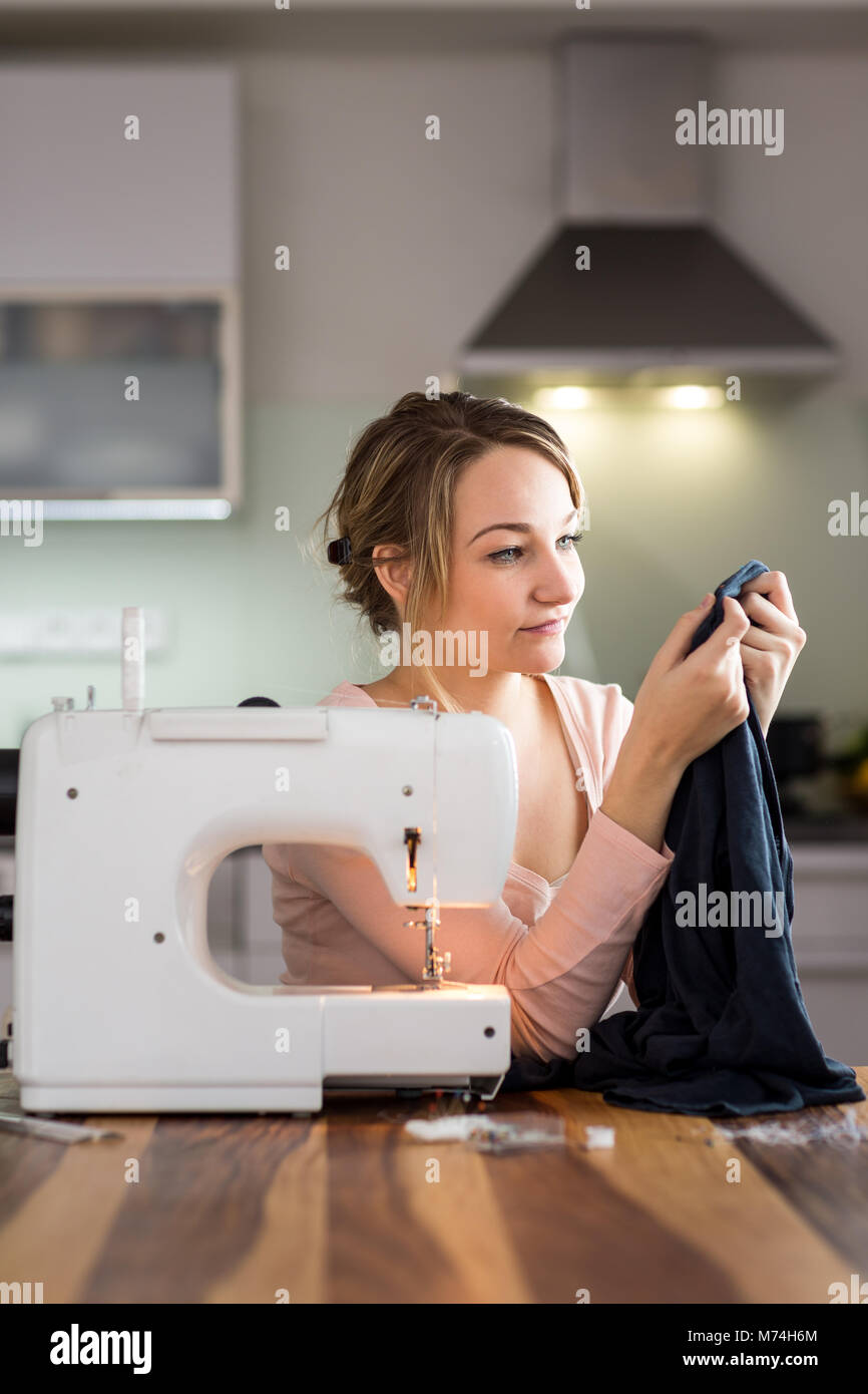 Beautiful young woman sewing clothes with sewing machine (color toned ...