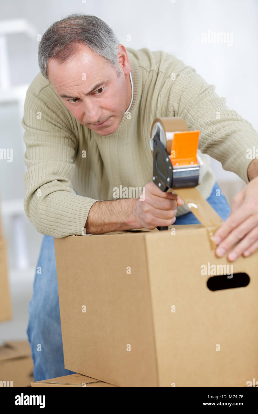 Man sealing cardboard box with brown tape Stock Photo - Alamy
