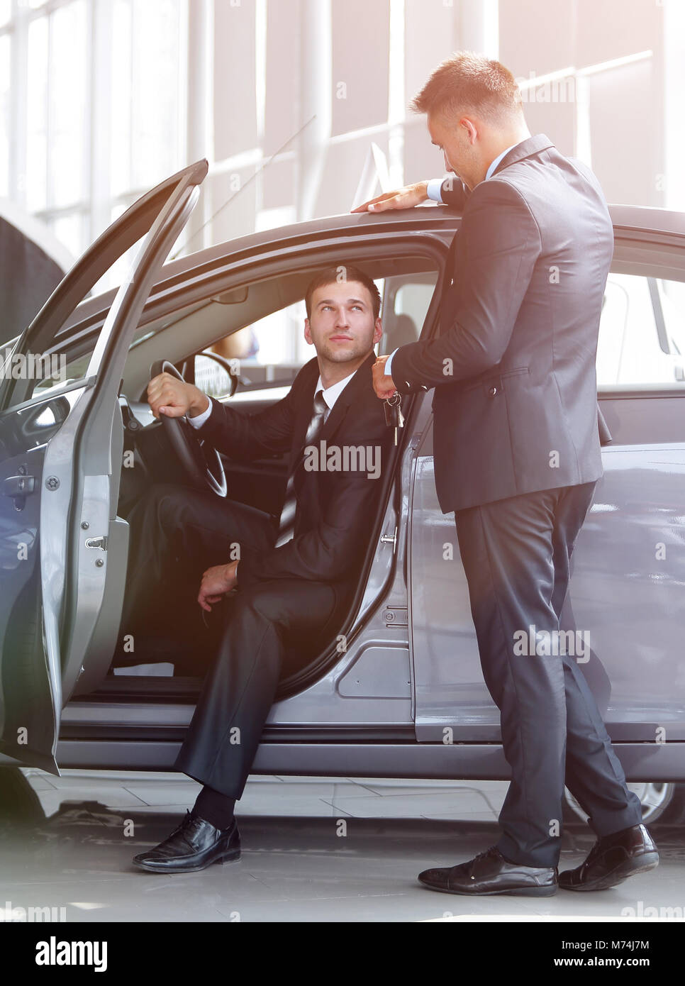 businessman receives from the Manager the keys,sitting behind the wheel ...