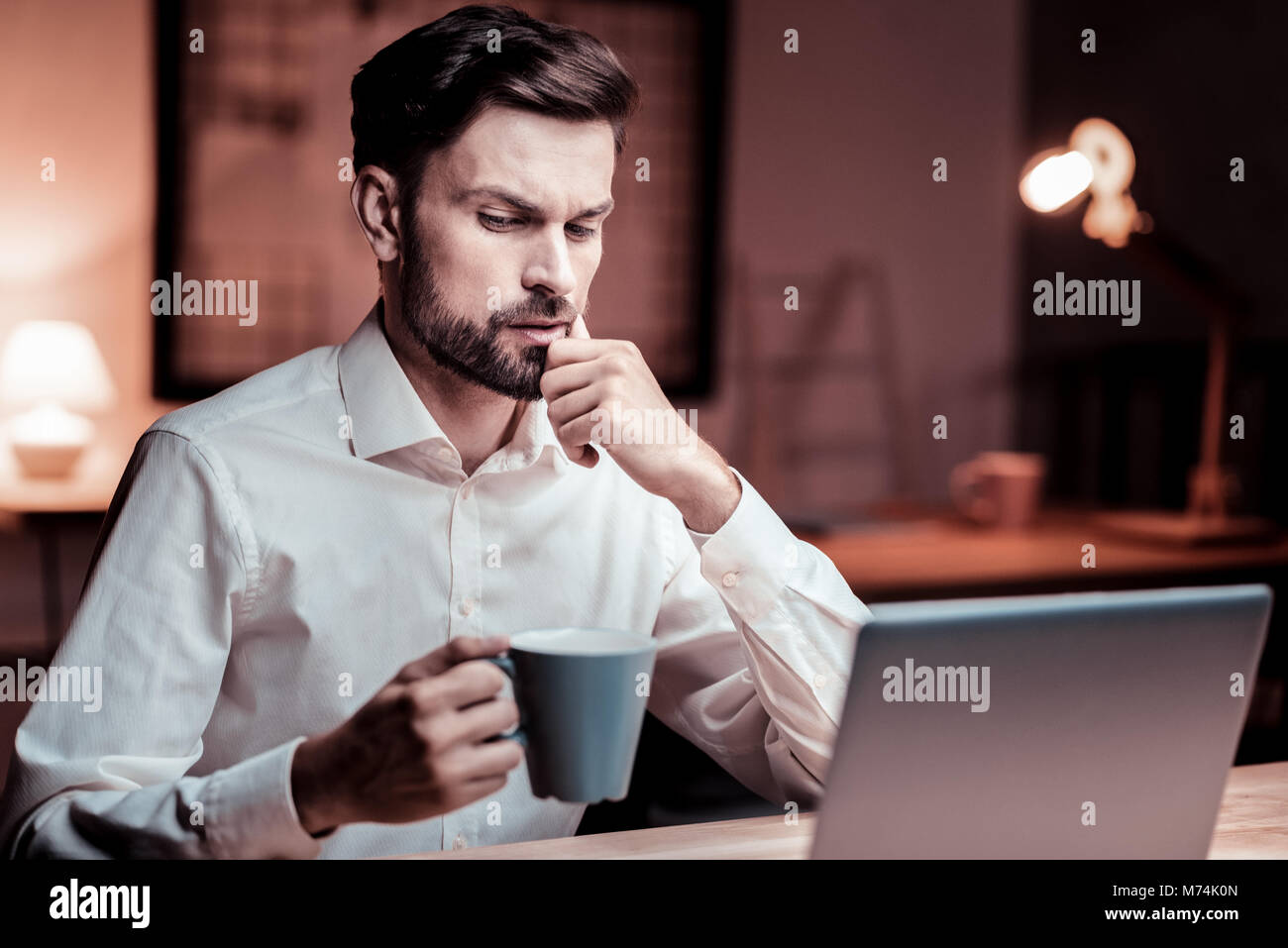 Serious concentrated man holding a cup and thinking Stock Photo - Alamy