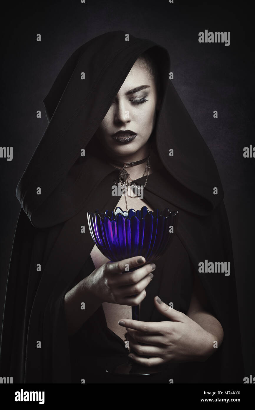 Beautiful vampire with a ritual cup. Hooded figure Stock Photo - Alamy