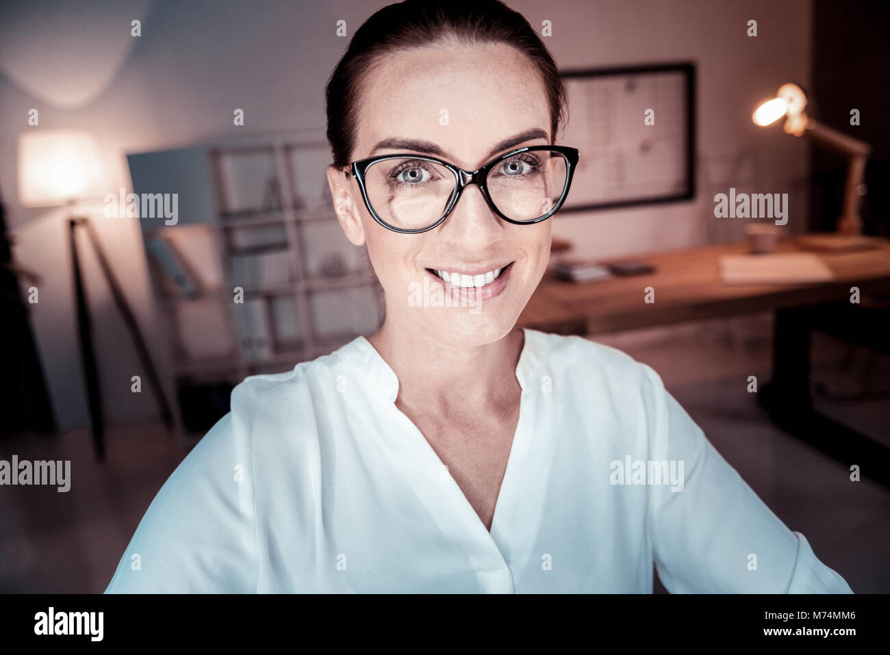 Bespectacled pleasant woman smiling and looking straight Stock Photo ...